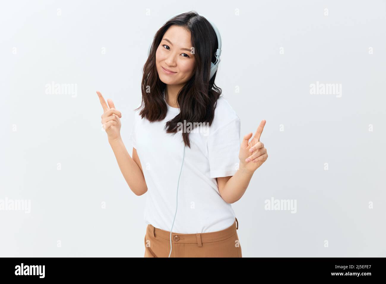 Enjoying happy joyful cute Asian young female in white basic t-shirt ...