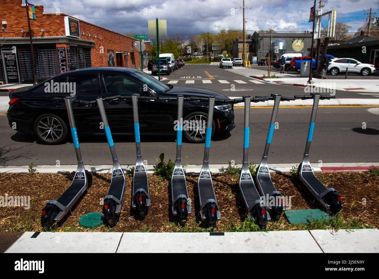 A car passes by electric scooters. Bird plans to launch 250 e-scooters ...