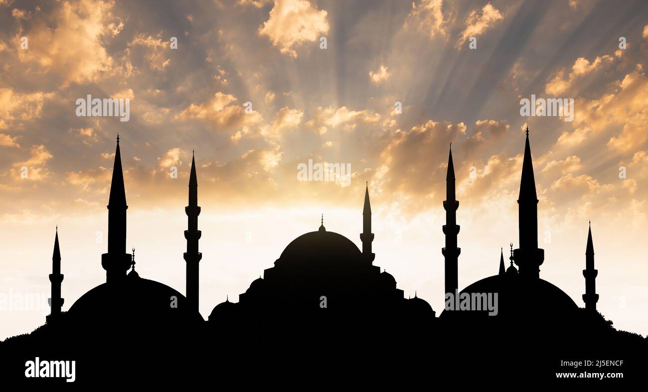 Mosque silhouette with orange sky and sunbeams at sunset. Ramadan and ...