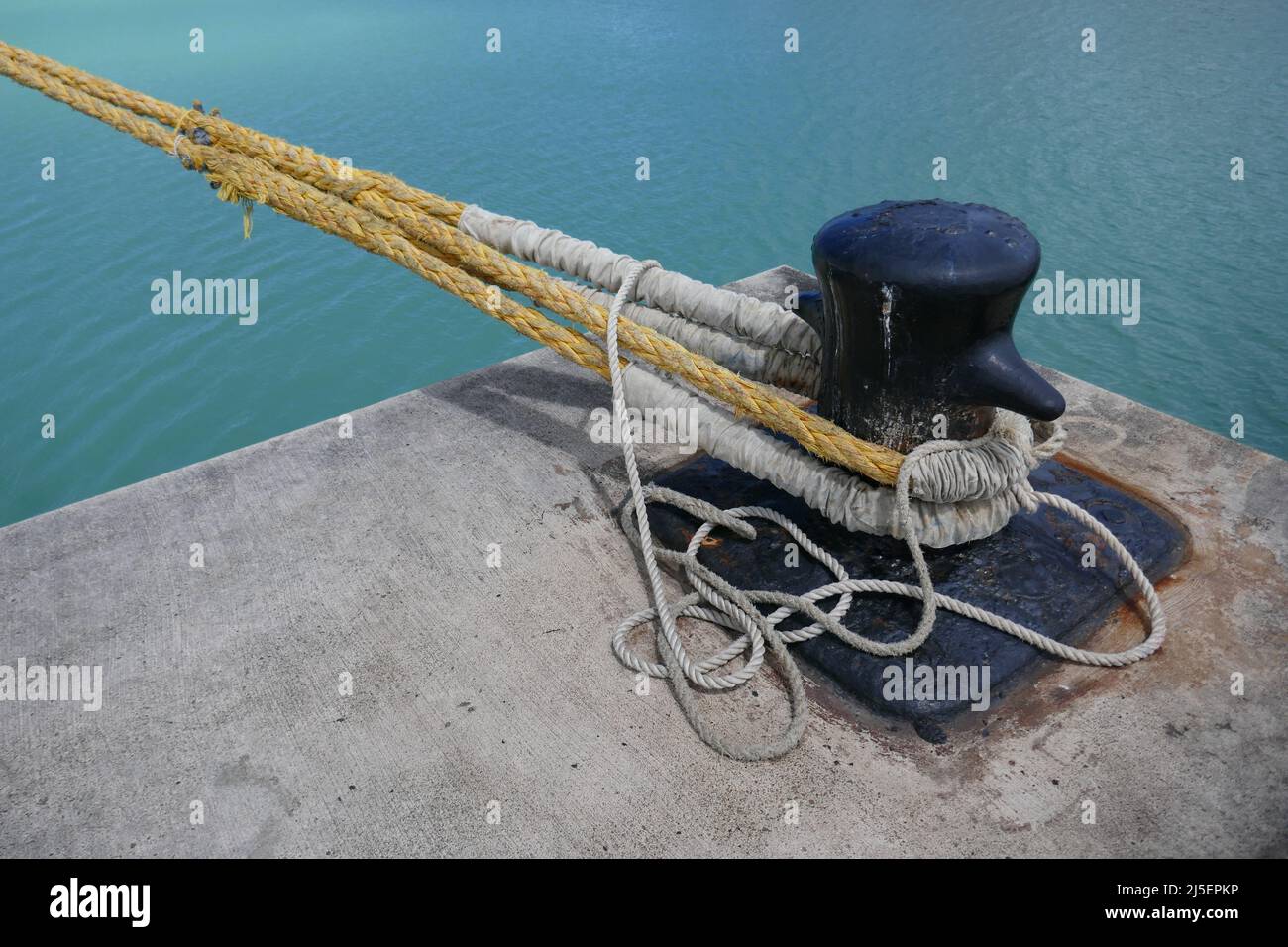 Ship Bollard with attached mooring lines mounted on concrete dock by ...