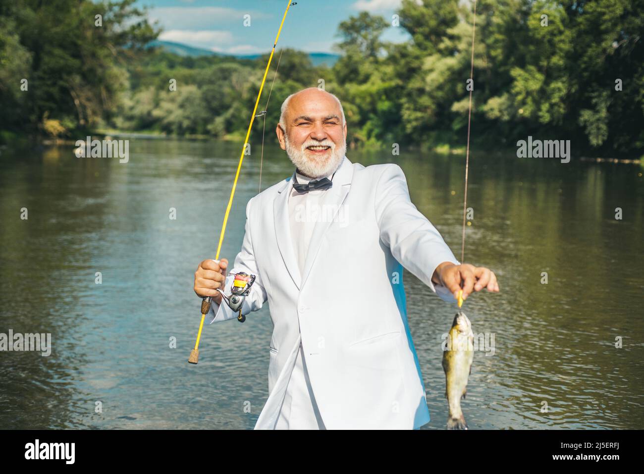 Happy old fisherman caught a trout fish. Portrait of cheerful smiling ...