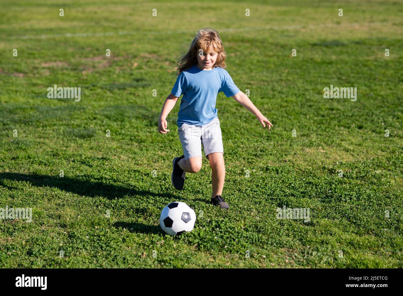 Soccer kid boy playing football. Child boy play football on outdoor field. Children score goal ...