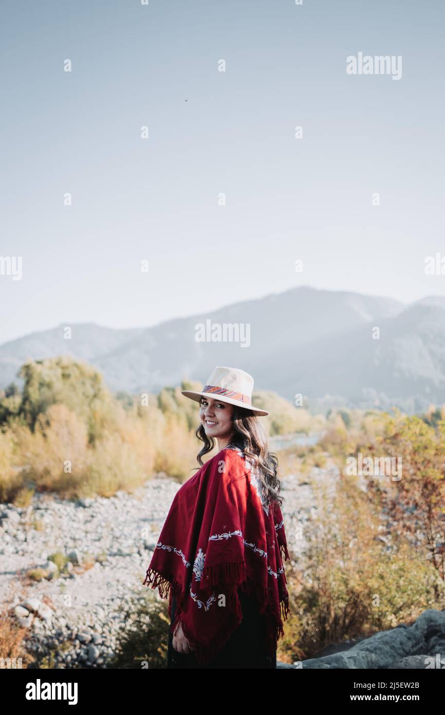Traditional latin american woman wearing a red poncho and a hat, in a ...