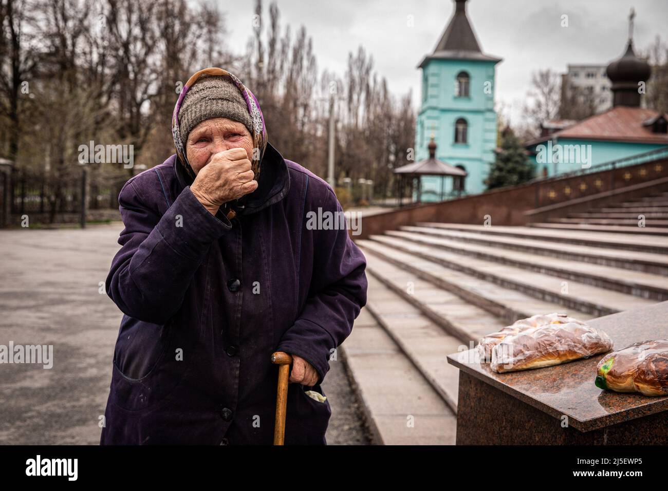 An elderly lady cries in front of the cathedral as she receives bread ...