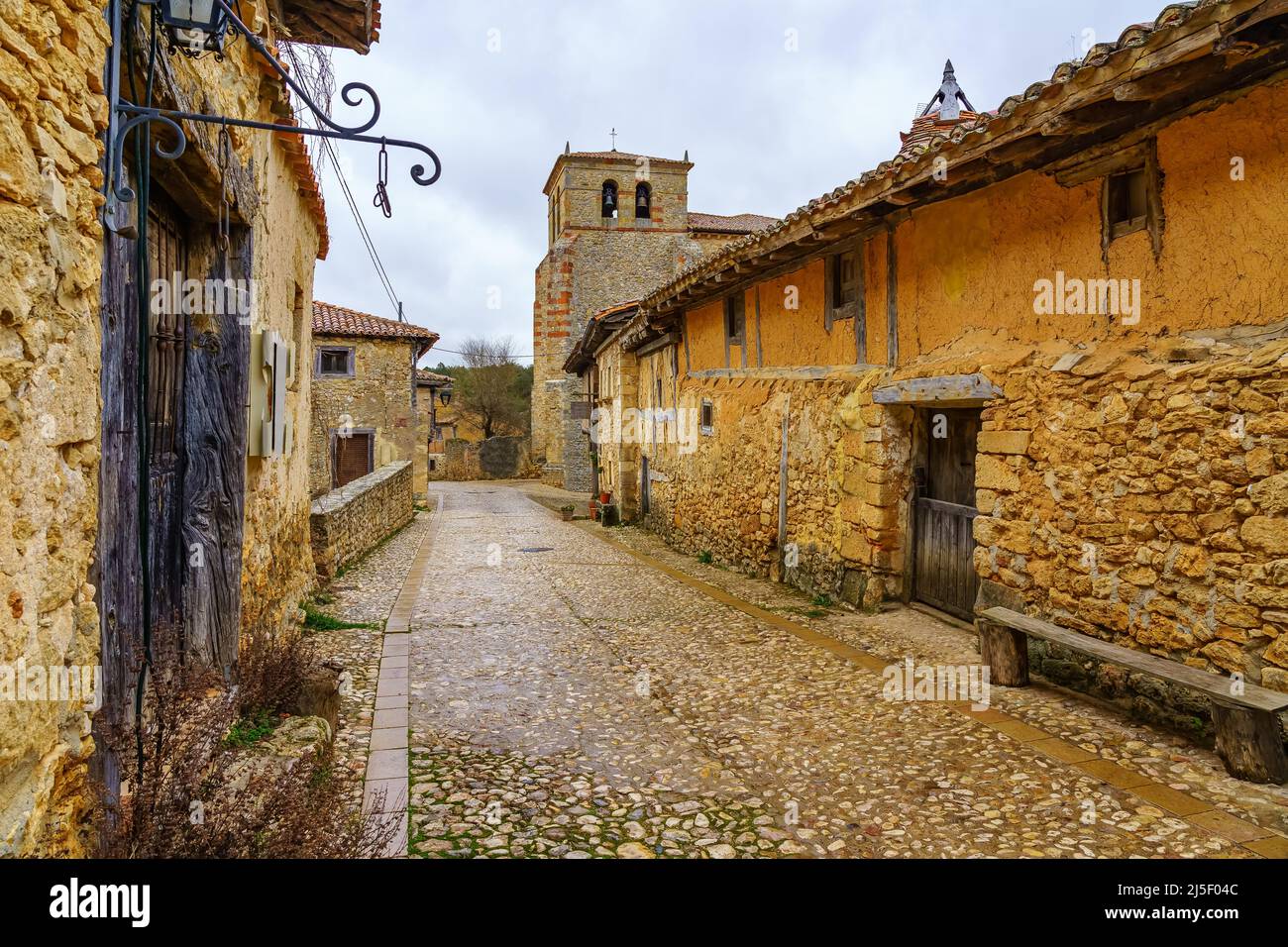 Narrow alley of medieval village and its church in the background ...