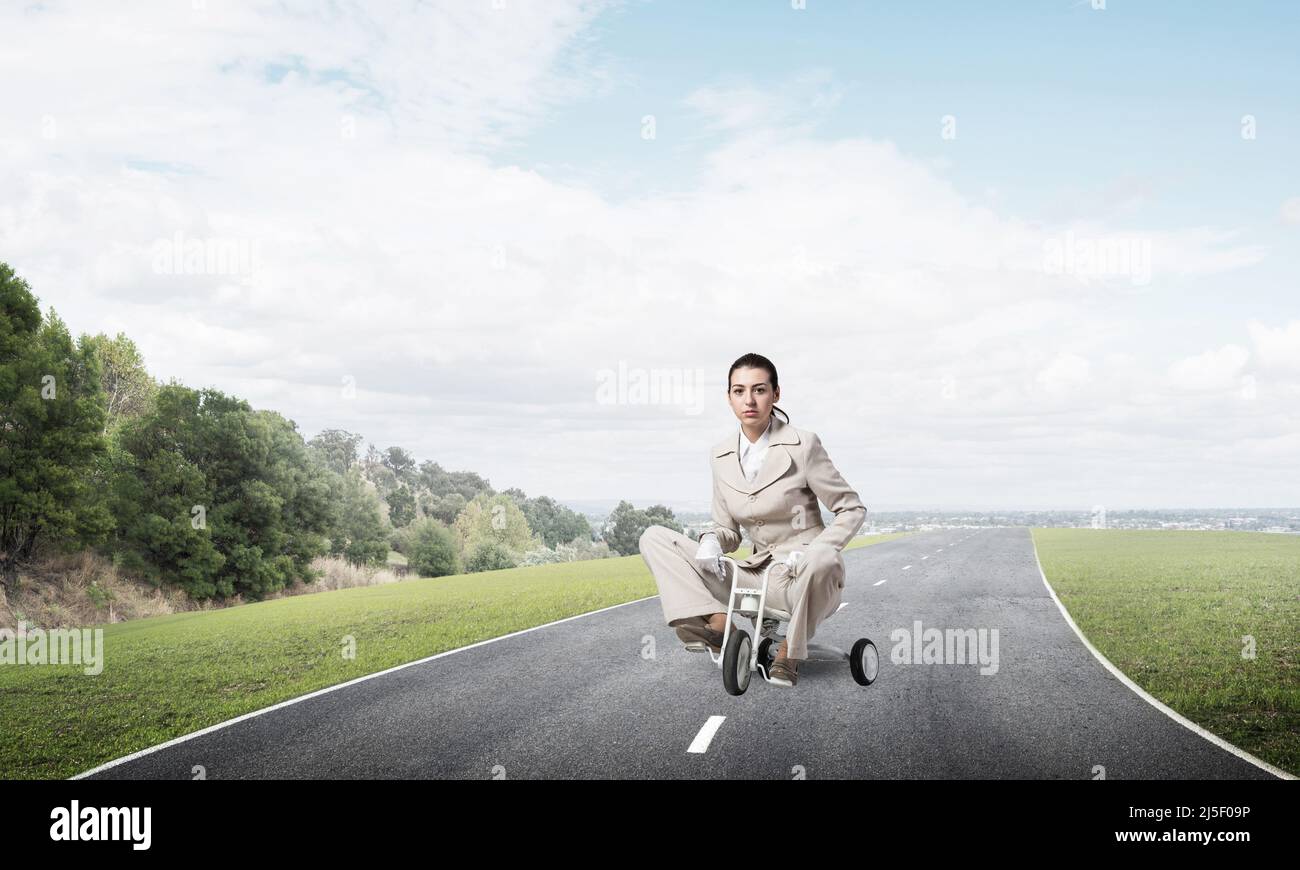 Caucasian woman riding kid's bicycle on road Stock Photo - Alamy