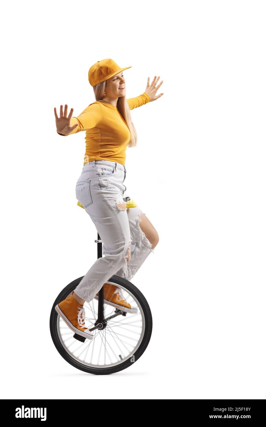 Full length side shot of a young female riding a unicycle isolated on ...
