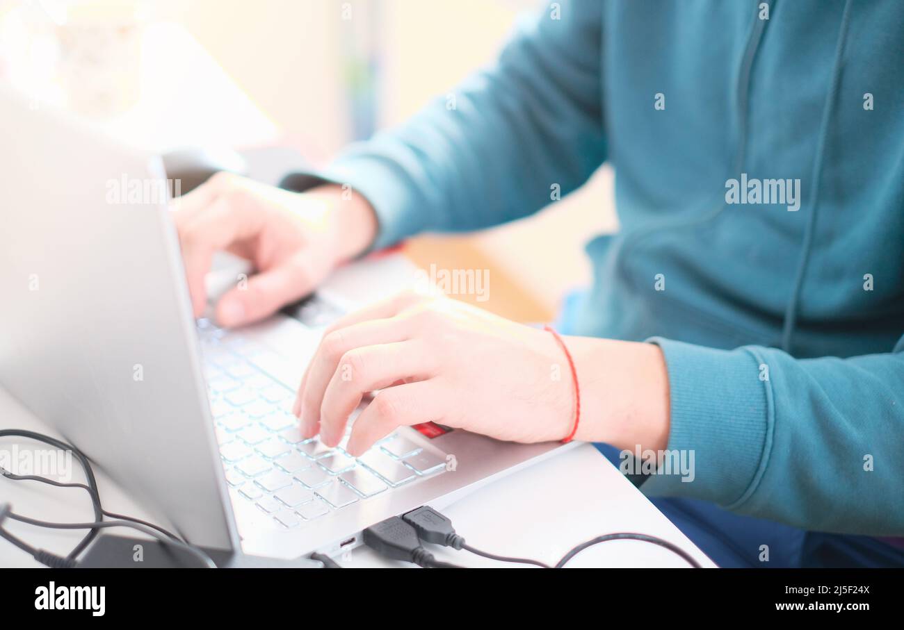 A man in a turquoise sweater in a bright office while working at a ...