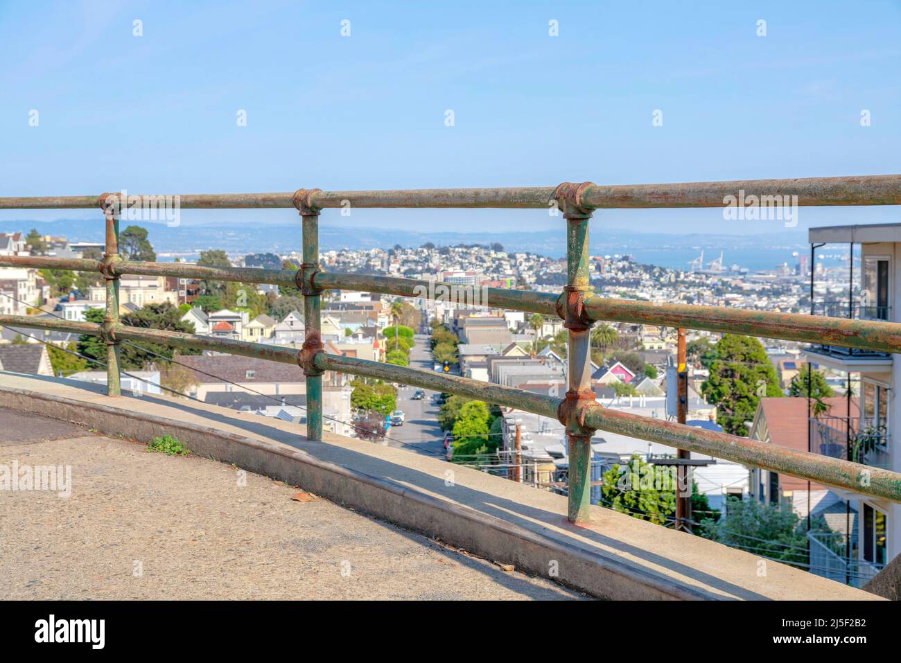 Rusty metal bar handrails with a view below of the neighborhood in San ...
