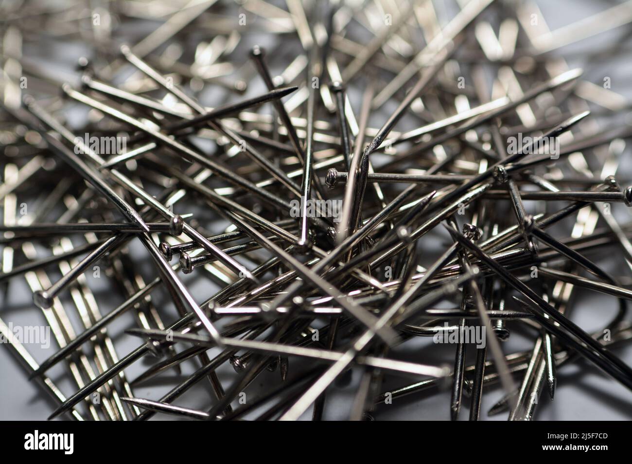 Selective focus of a pile of Nickel plated steel pins, stack of paper ...