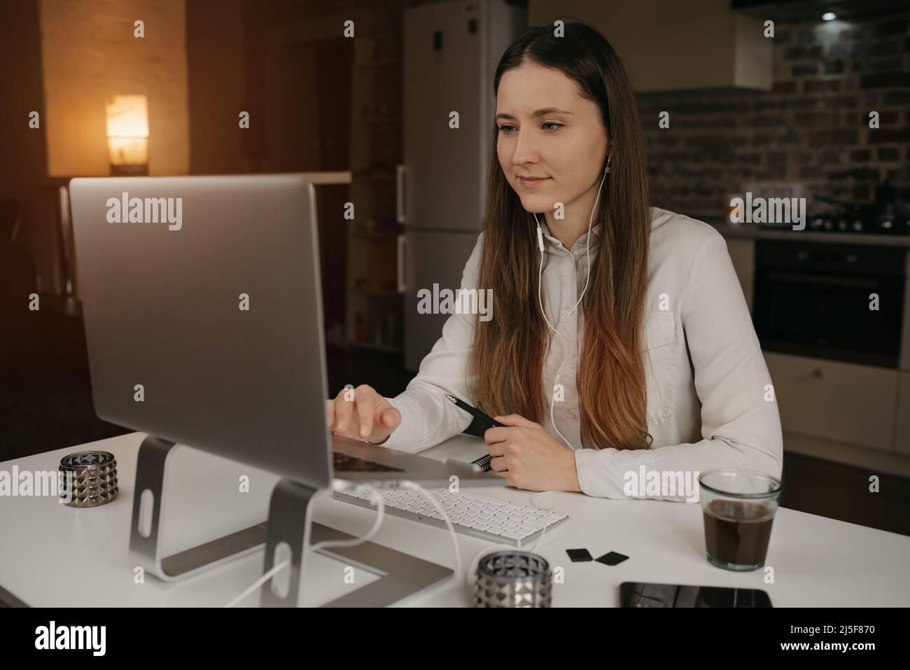 A caucasian woman with headphones working remotely on her laptop at ...