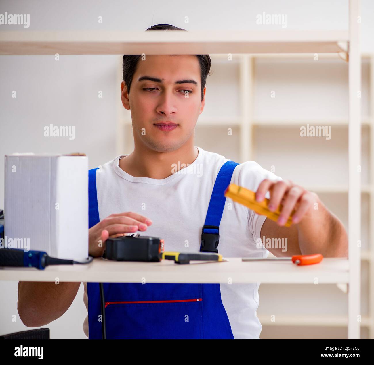 The worker man repairing assembling bookshelf Stock Photo - Alamy