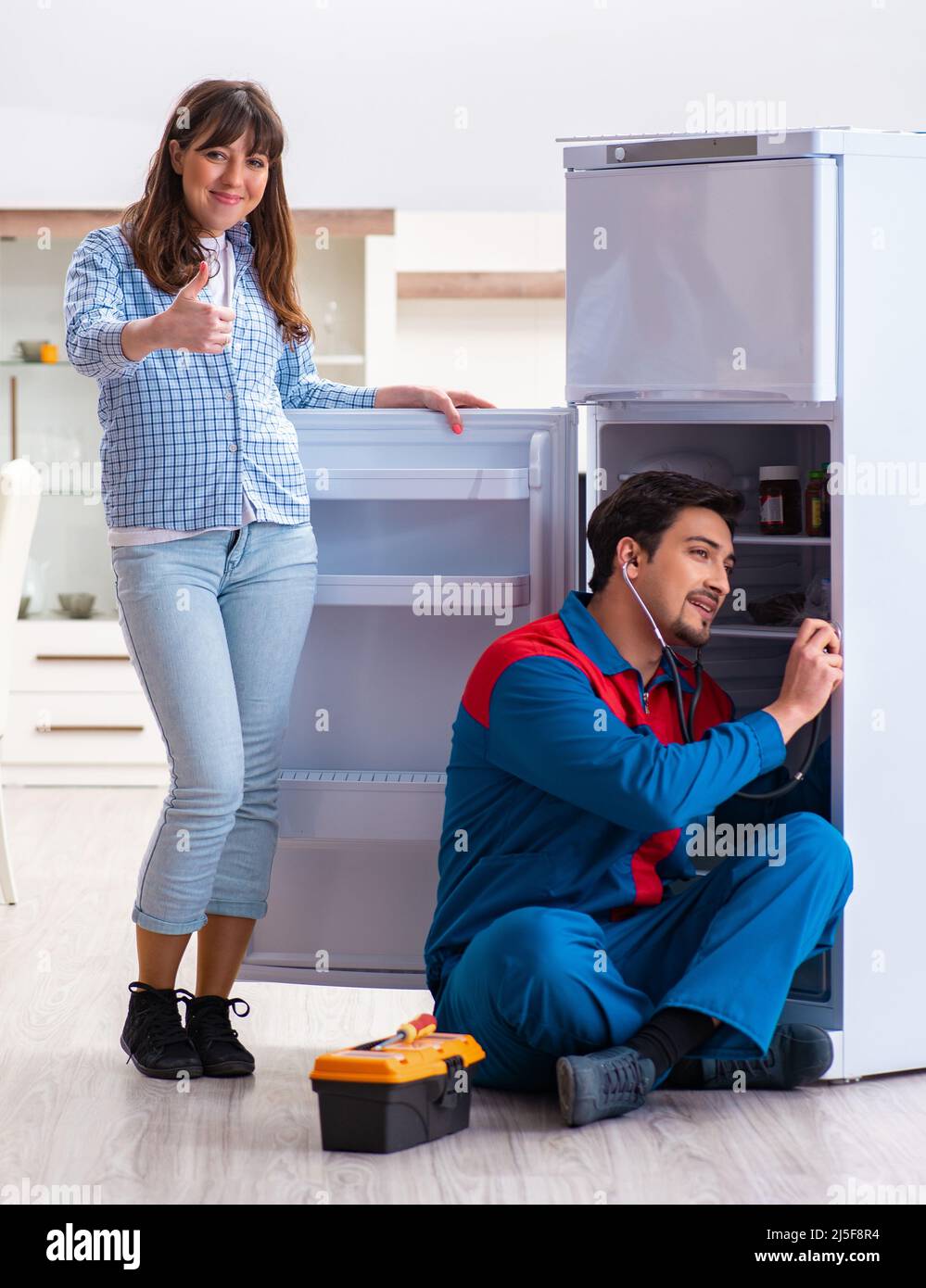 The man repairing fridge with customer Stock Photo - Alamy