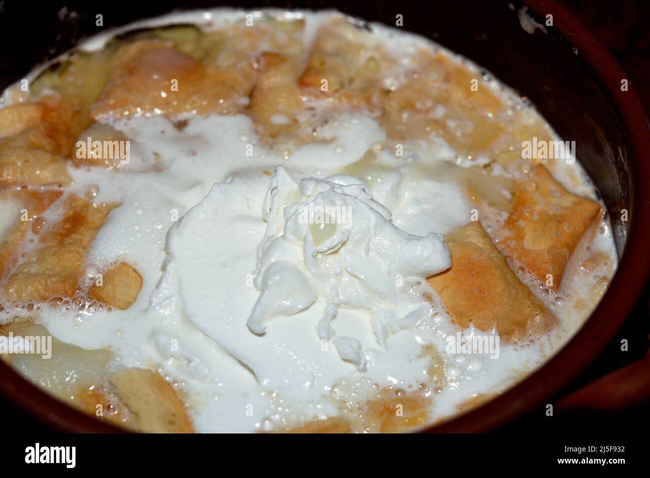 whipped cream on top of Egyptian bread pudding, milk in a brown bowl ...