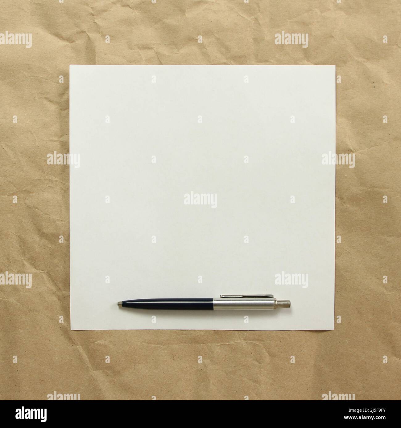Square white empty sheet of paper with pen on a beige craft paper ...
