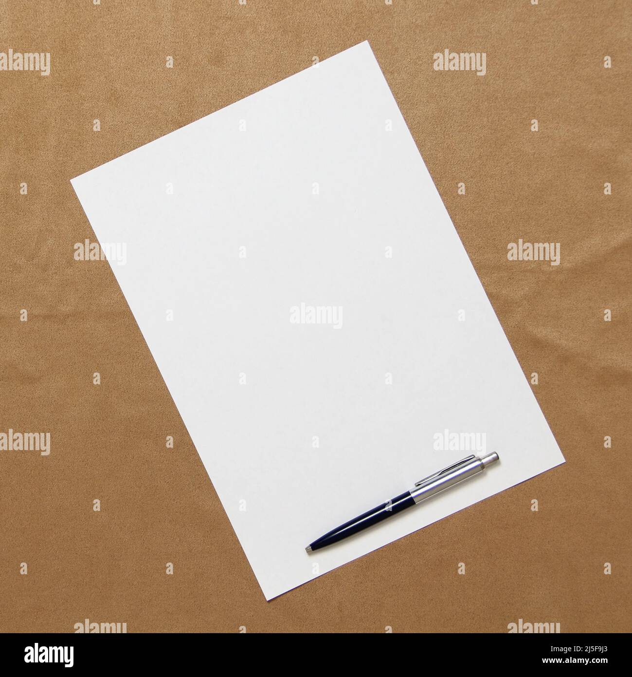 Template of white paper with pen lies diagonally on light brown cloth ...