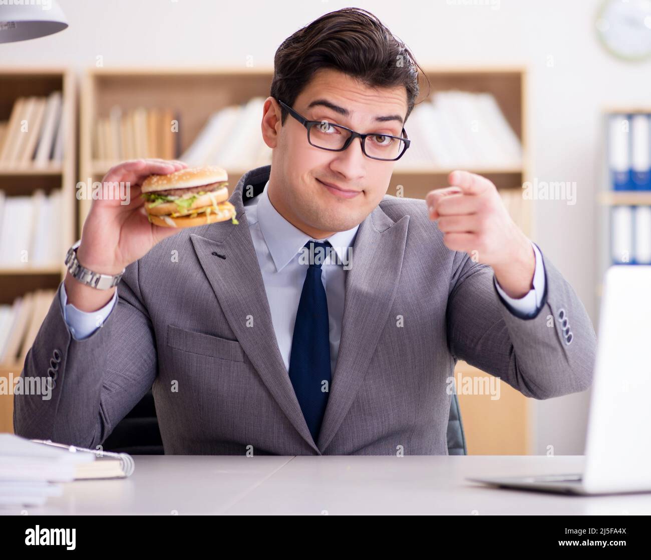 The hungry funny businessman eating junk food sandwich Stock Photo - Alamy