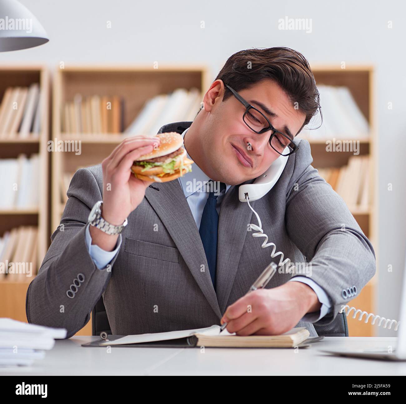 The hungry funny businessman eating junk food sandwich Stock Photo - Alamy