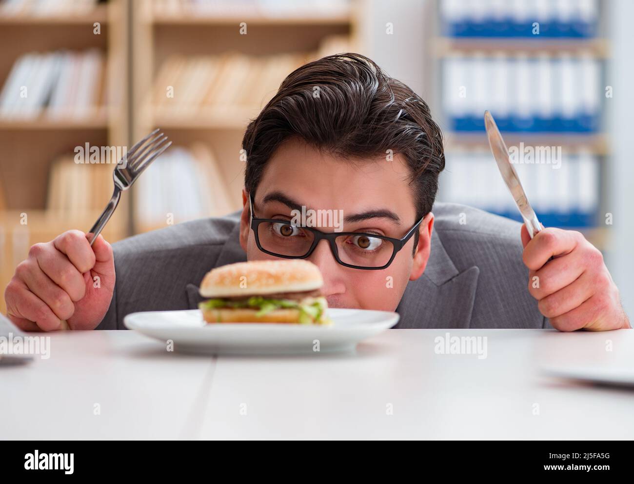 The hungry funny businessman eating junk food sandwich Stock Photo - Alamy