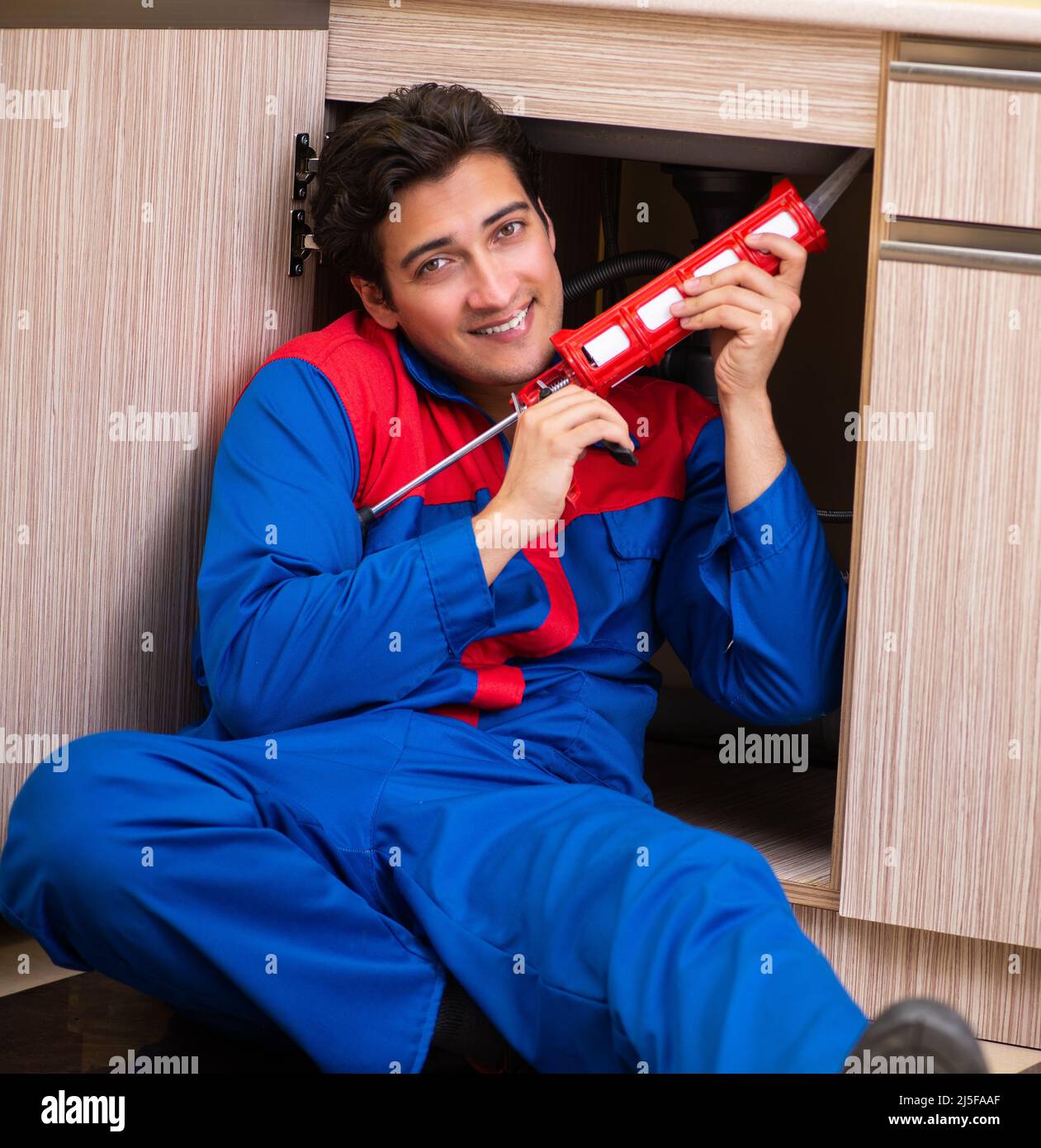 The plumber repairing wash basin at kitchen Stock Photo - Alamy