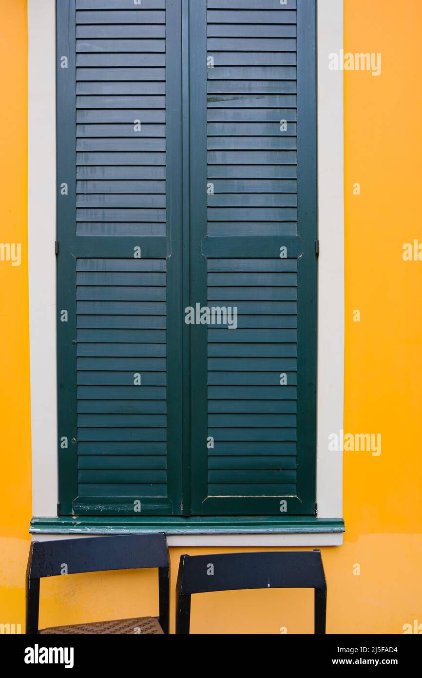 closed wooden window with shutters and chairs. colorful city street ...