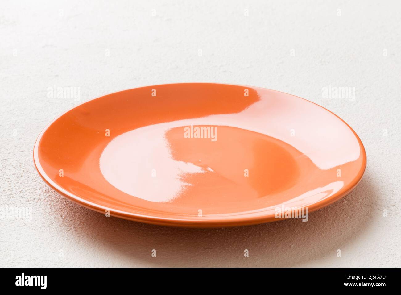 Perspective view of empty orange plate on cement background. Empty ...