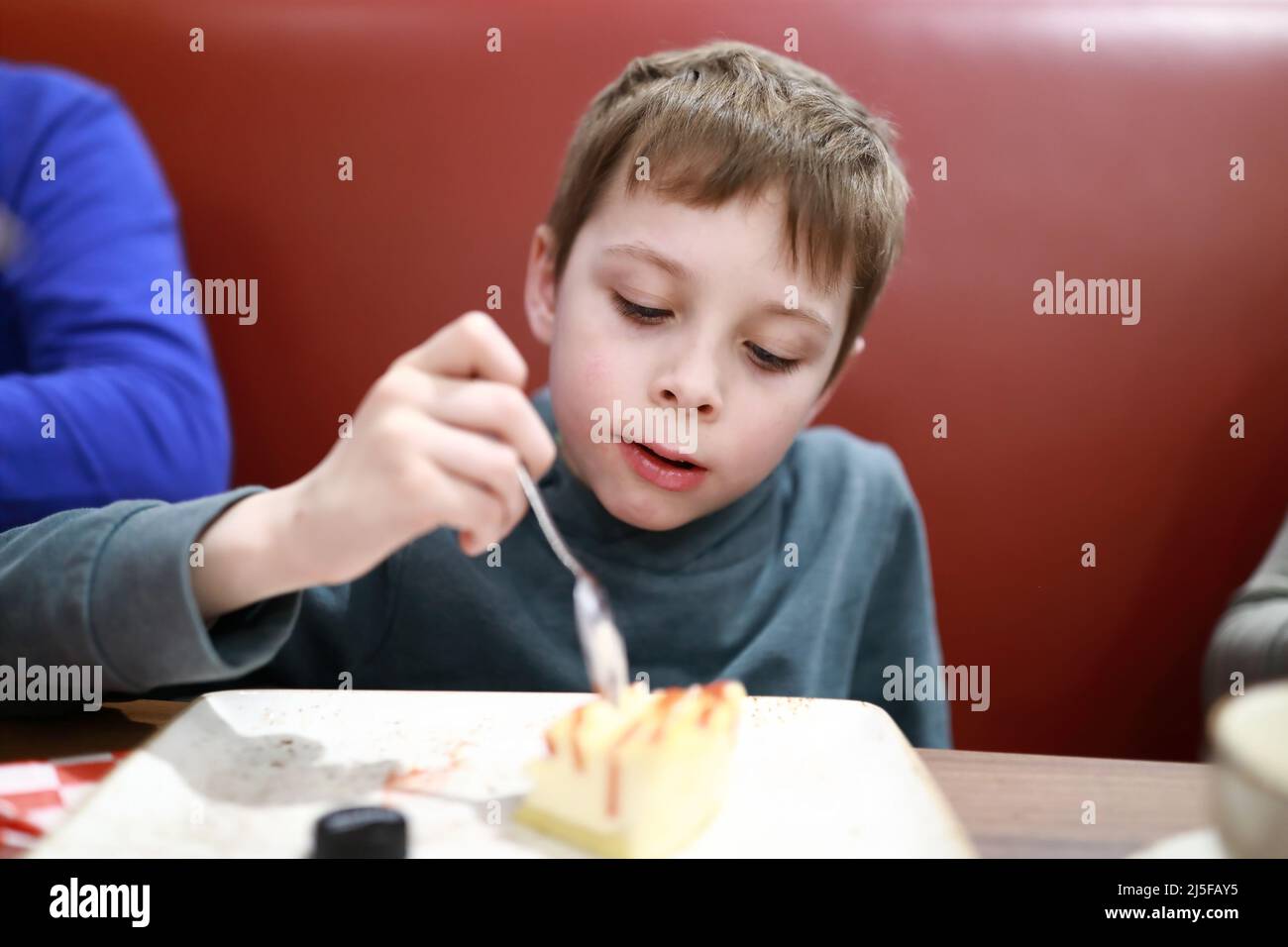 Portrait of boy eating cheesecake in restaurant Stock Photo - Alamy