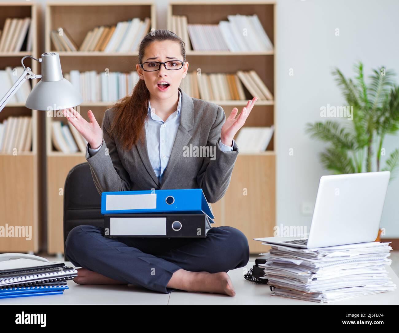 The busy angry businesswoman sitting on the desk in office Stock Photo ...