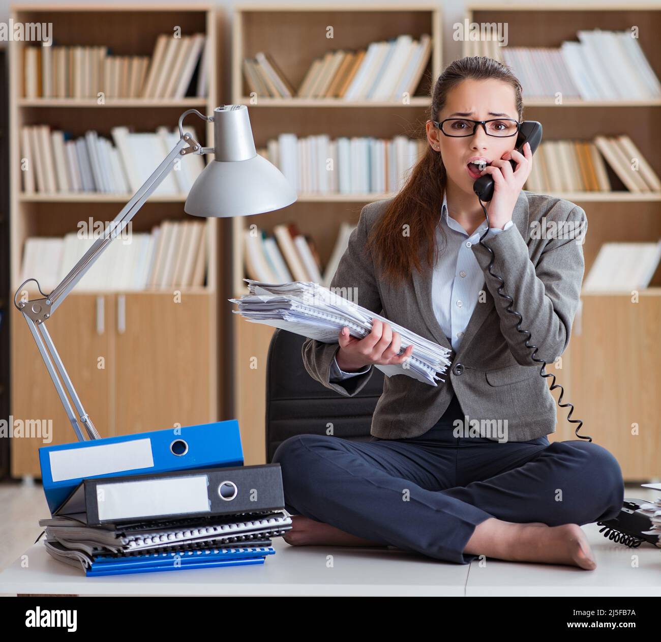The busy angry businesswoman sitting on the desk in office Stock Photo ...