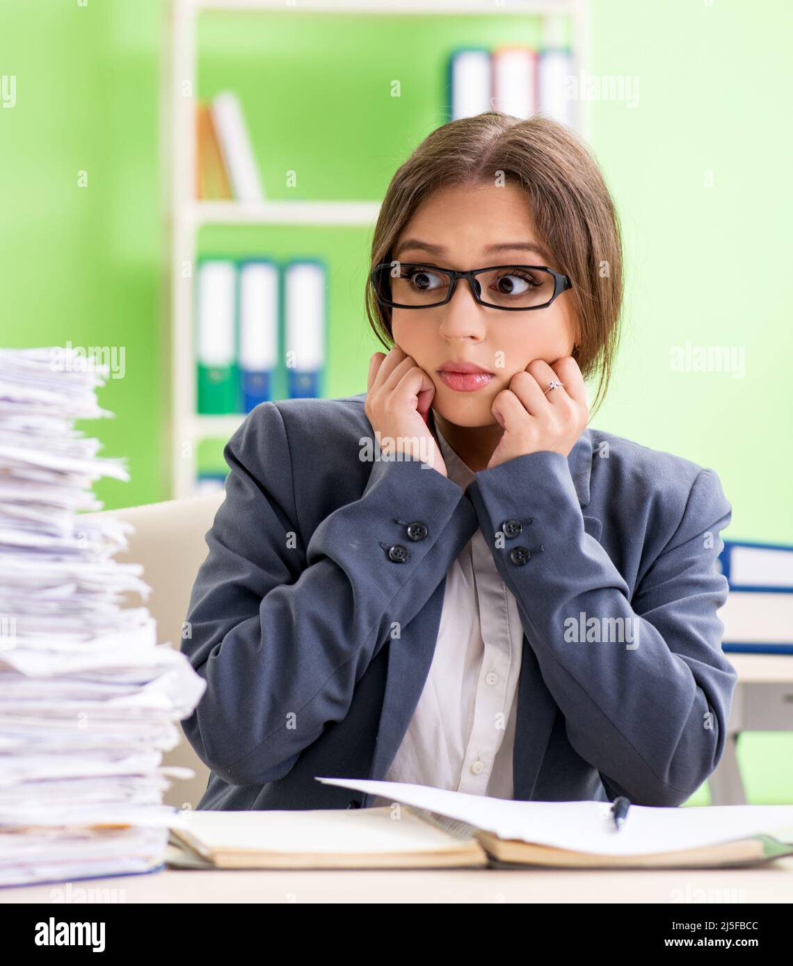 The young female employee very busy with ongoing paperwork Stock Photo ...
