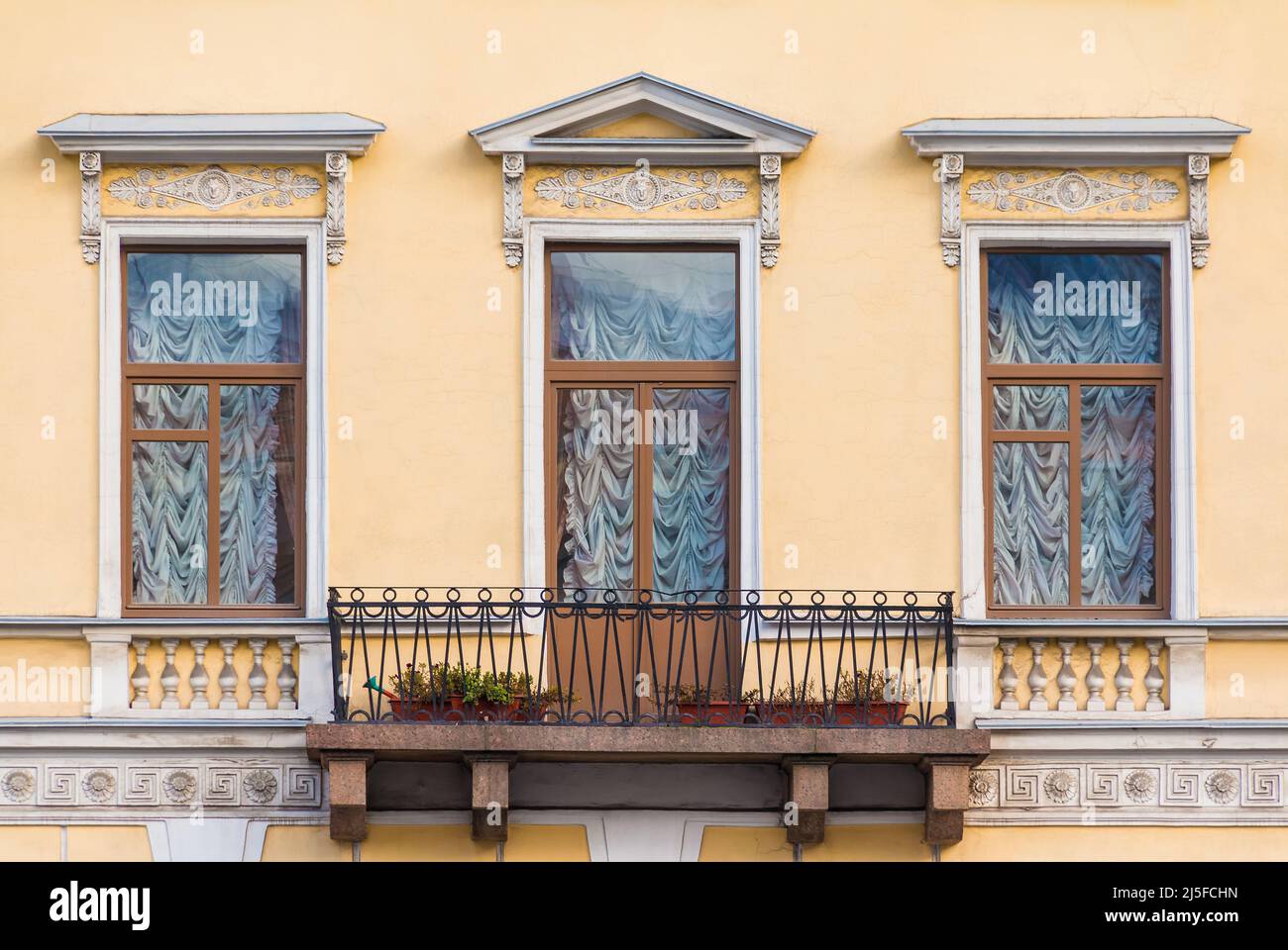 Balcony and three windows in a row on the facade of the urban historic ...