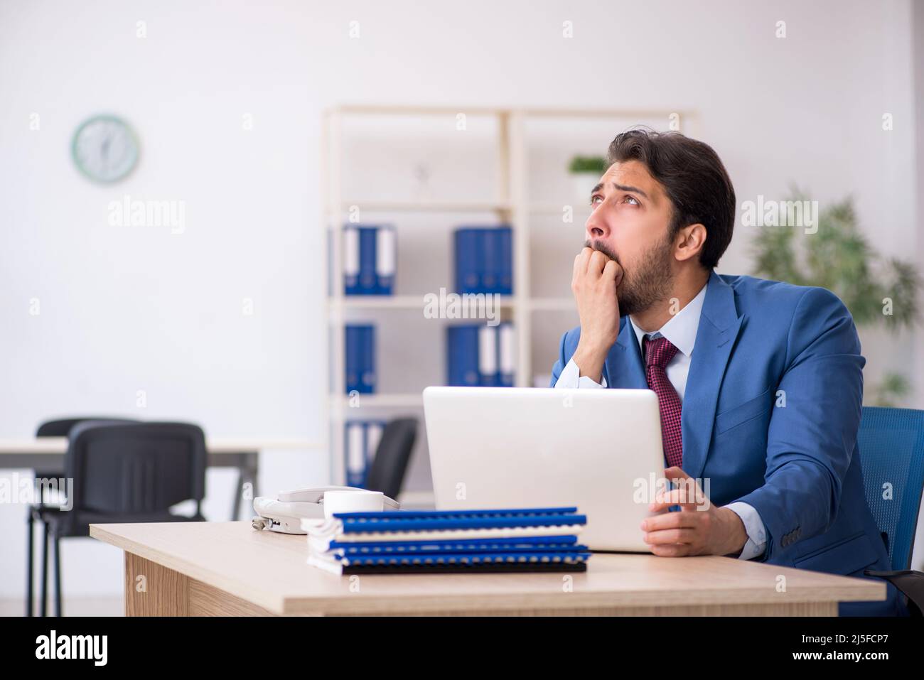 Young male employee and too much work in the office Stock Photo - Alamy