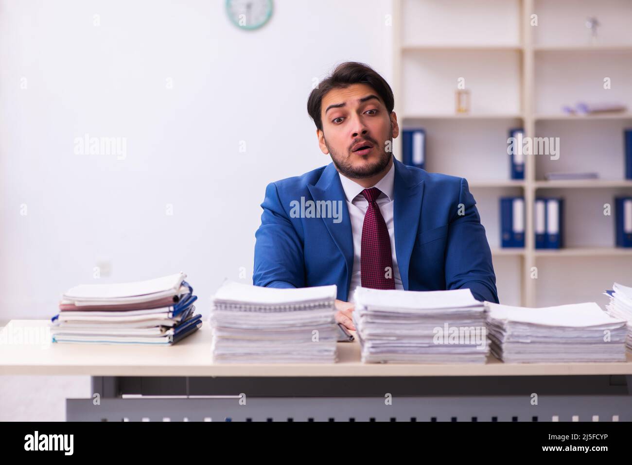 Young male employee and too much work in the office Stock Photo - Alamy