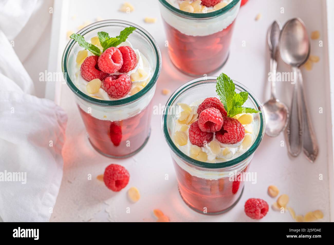 Homemade red jelly with raw raspberries and whipped cream. Raspberries ...
