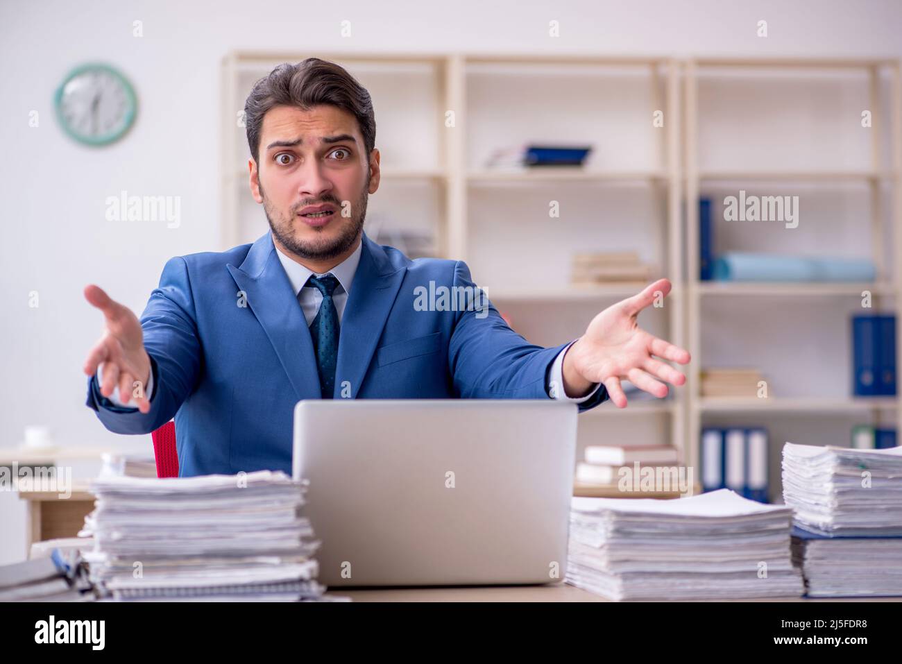 Young male employee and too much work in the office Stock Photo - Alamy