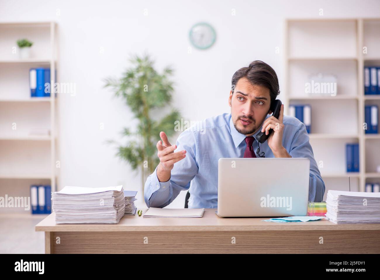 Young employee and too much work in the office Stock Photo - Alamy