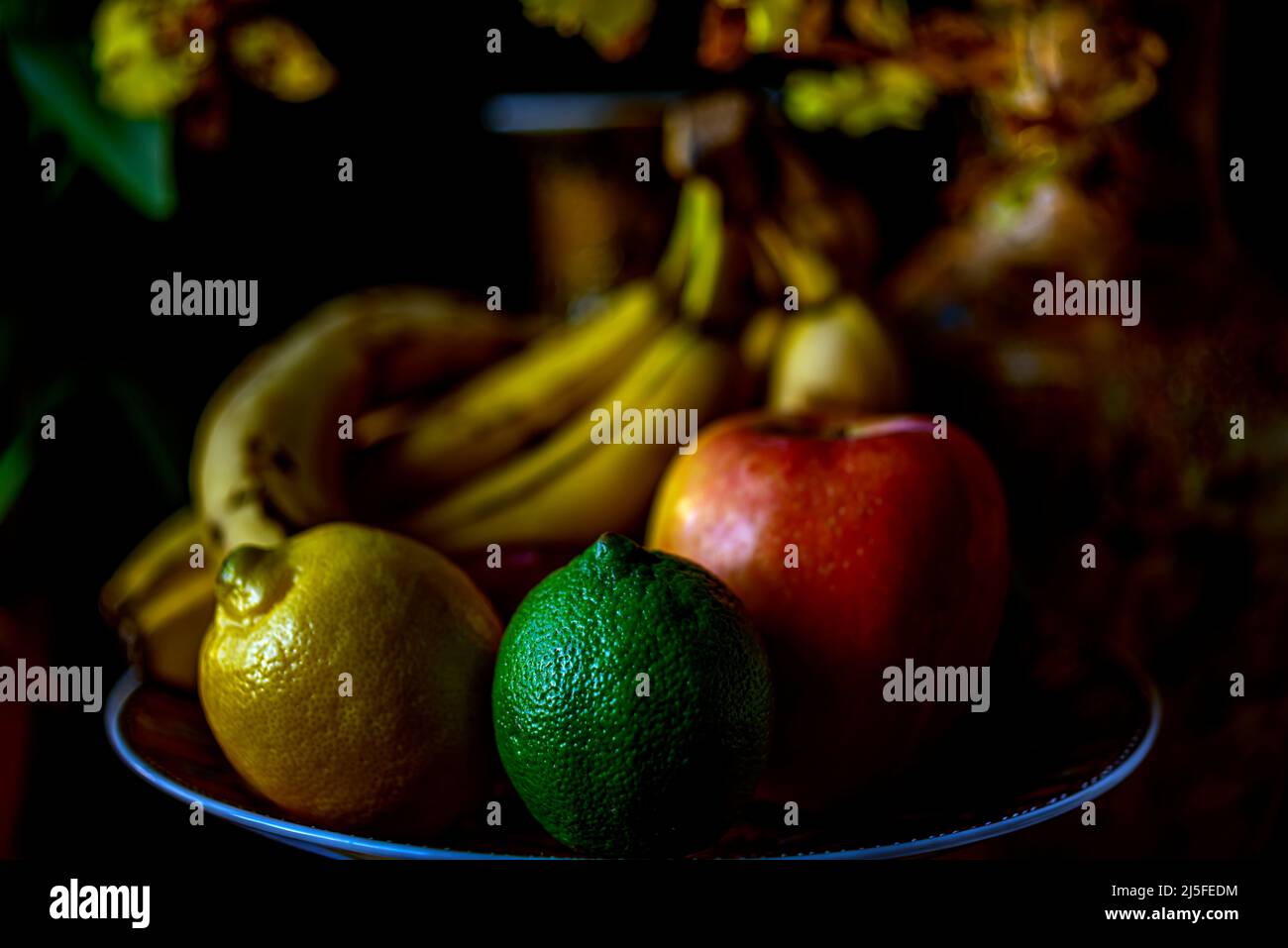 Dark still life of fruit on a plate with black background Stock Photo ...