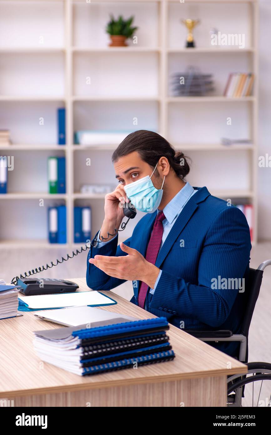 Young male disabled employee during pandemic at workplace Stock Photo ...