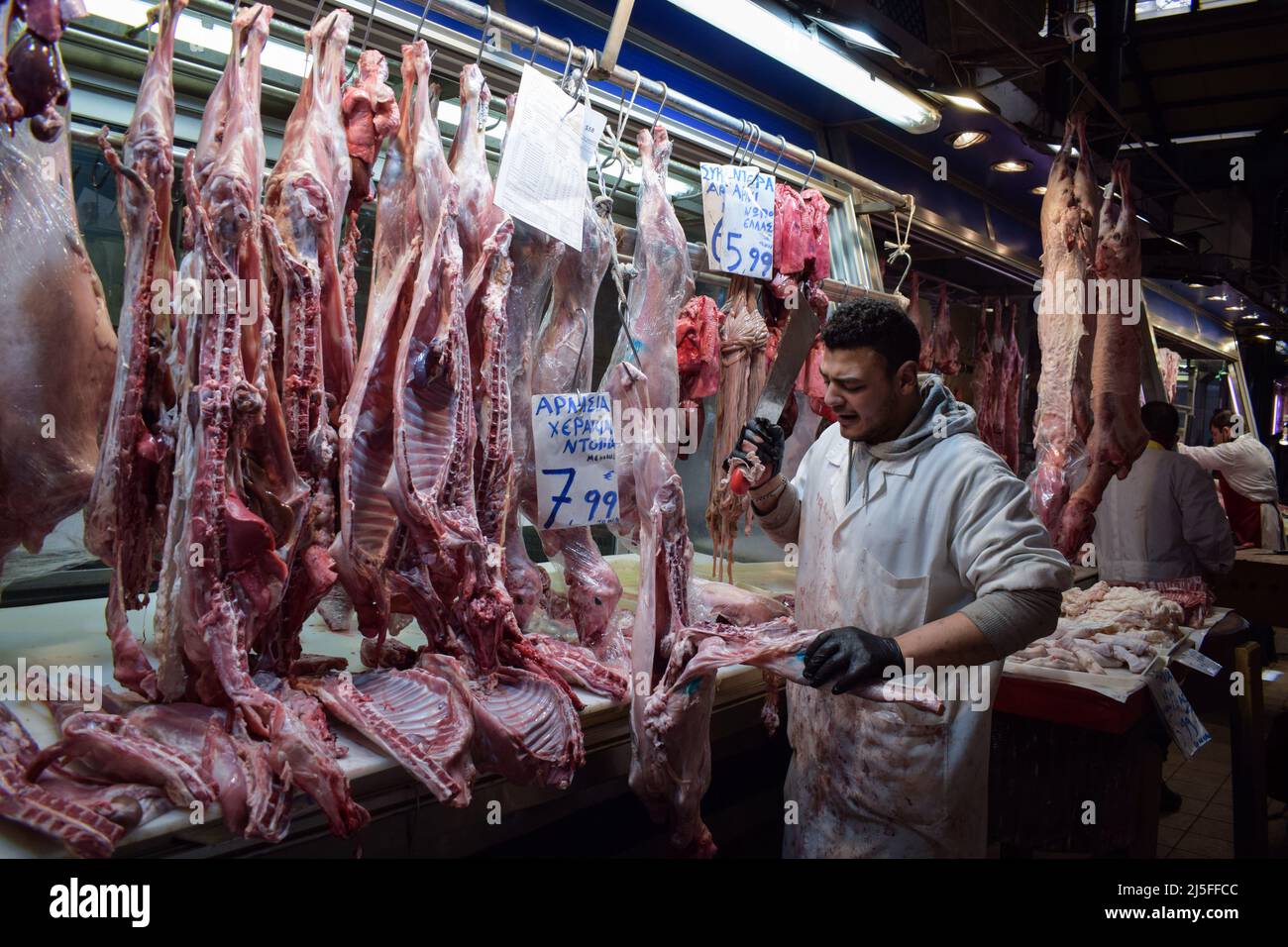 Athens, Greece. 21st Apr, 2022. A butcher is seen cutting meat into ...