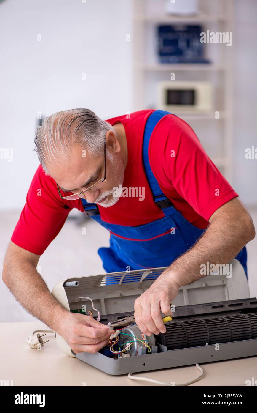 Old male repairman repairing air-conditioner Stock Photo - Alamy