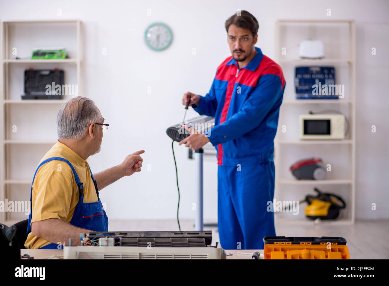Two repairmen working at workshop Stock Photo - Alamy