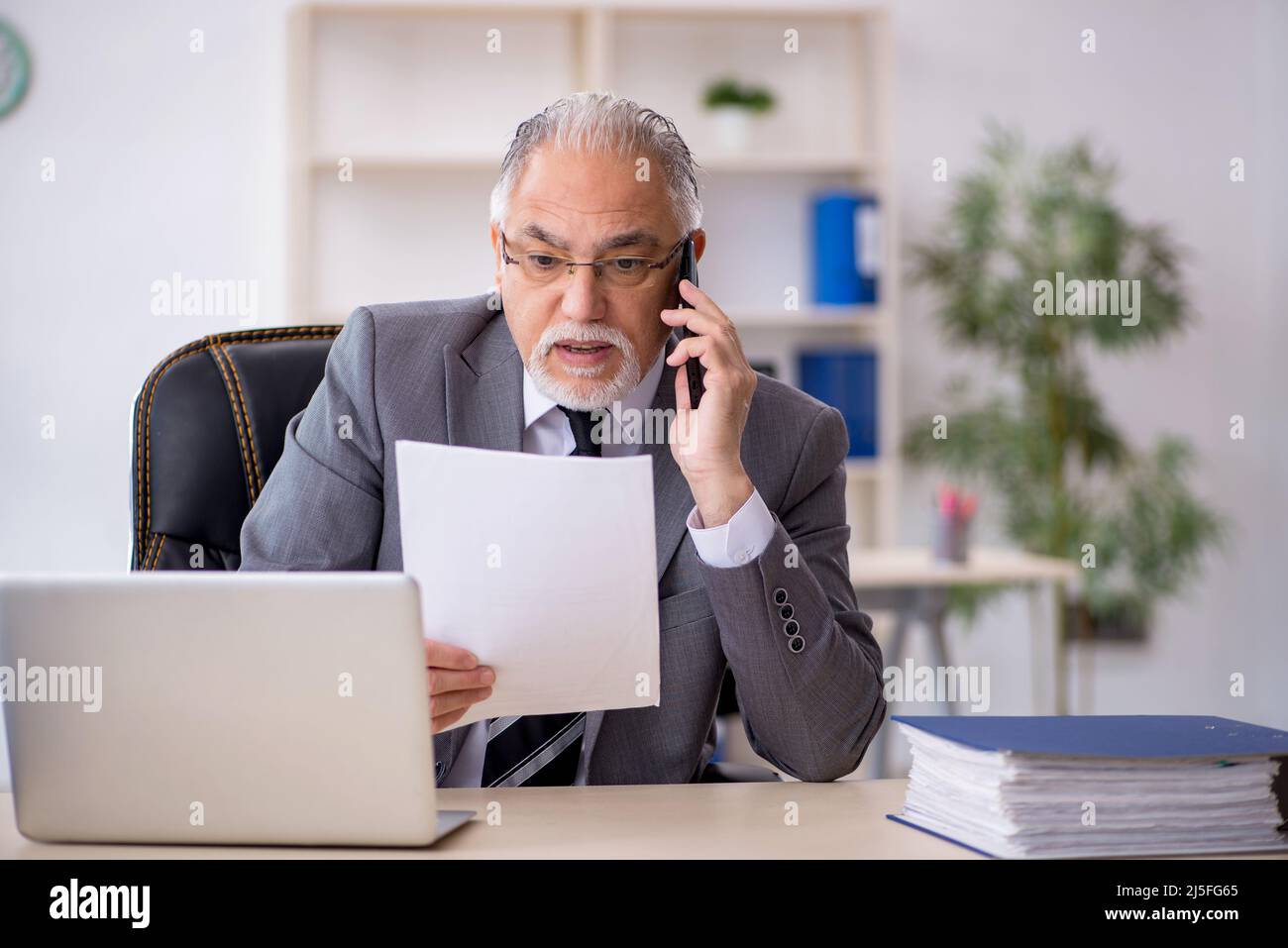 Aged male employee sitting at workplace Stock Photo - Alamy