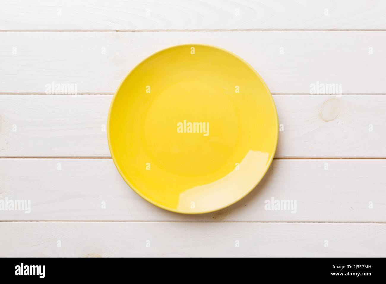 Top view of empty yellow plate on wooden background. Empty space for ...
