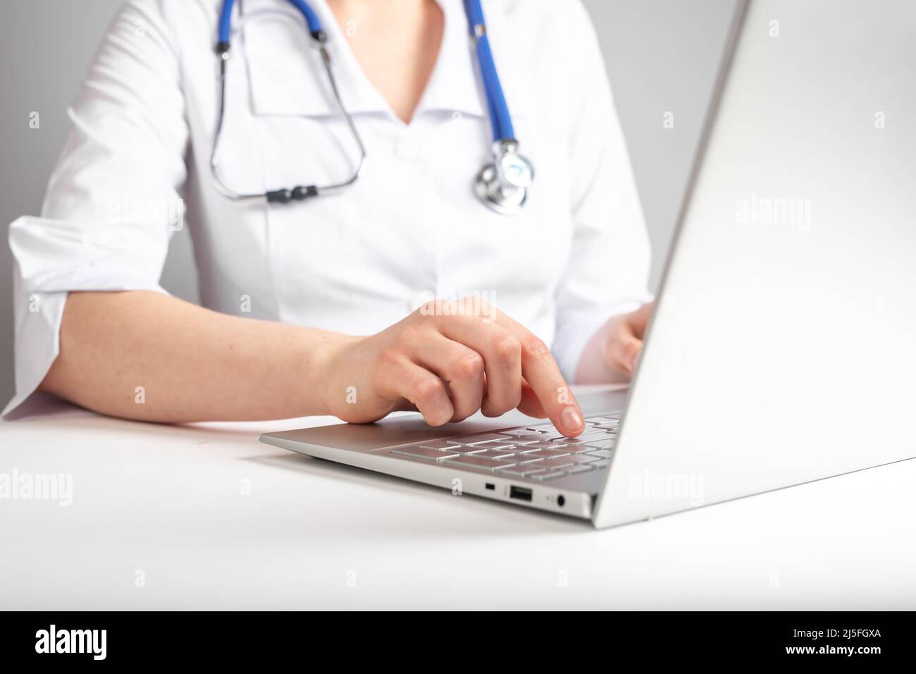 Doctor with stethoscope typing on laptop keyboard. Health care and ...