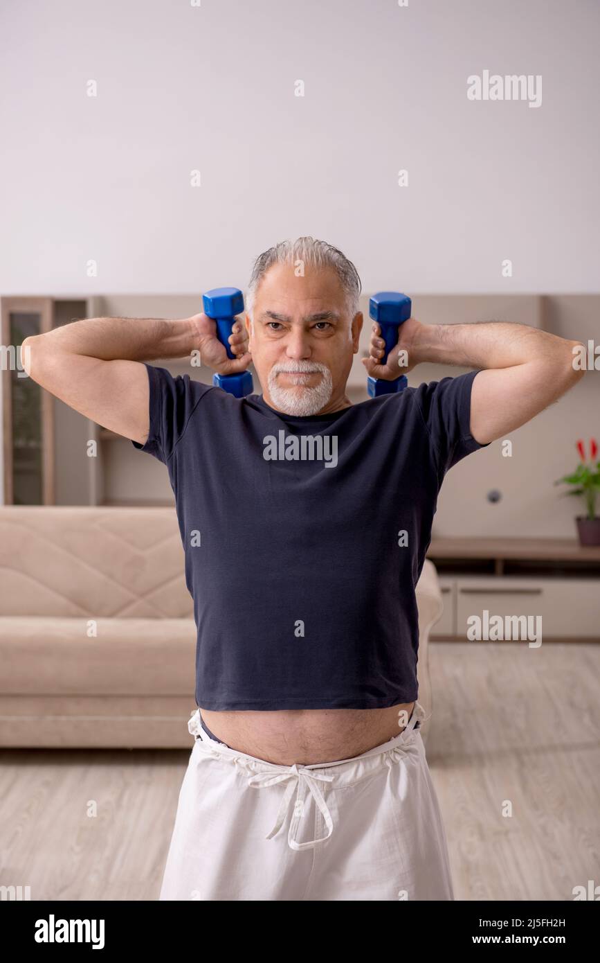 Old man doing sport exercises indoors Stock Photo - Alamy