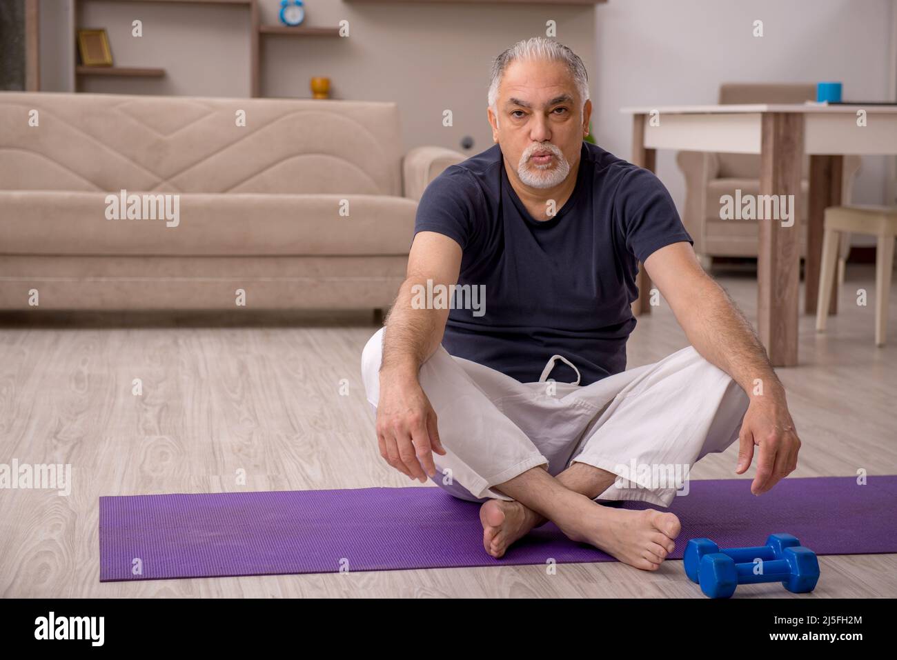 Old man doing sport exercises indoors Stock Photo - Alamy