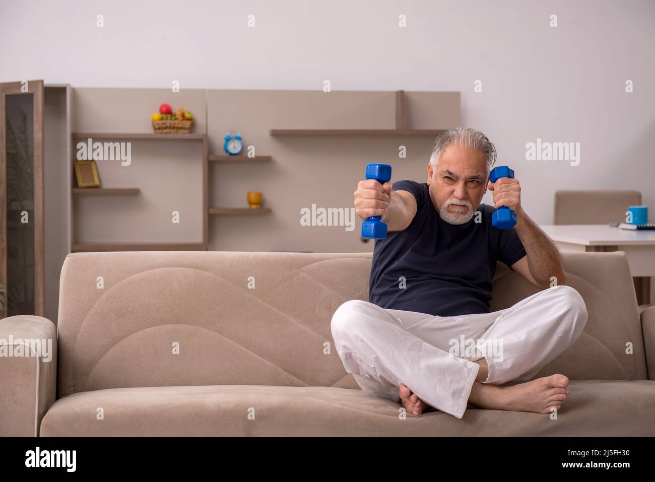Old man doing sport exercises indoors Stock Photo - Alamy