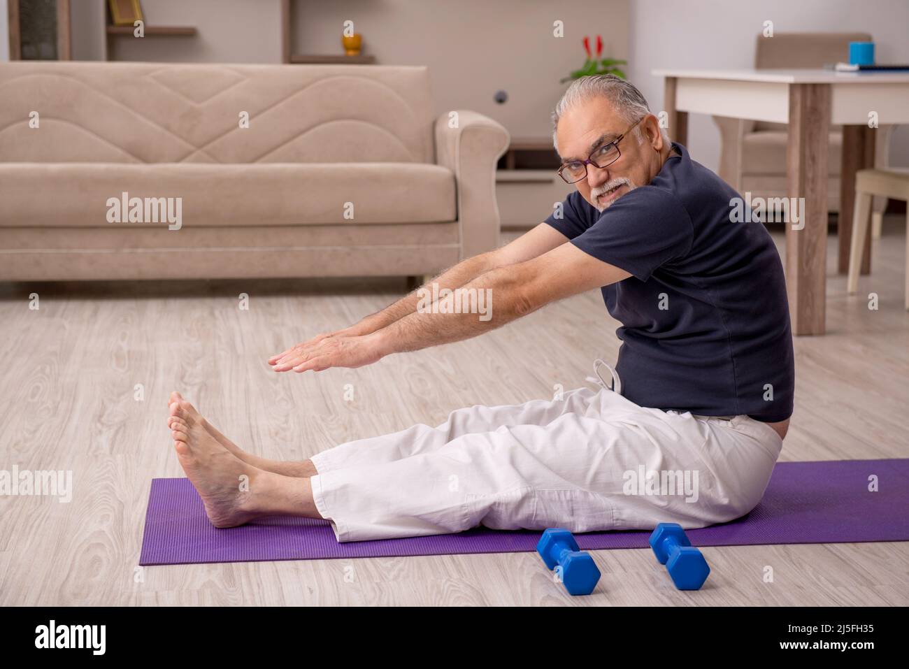 Old man doing sport exercises indoors Stock Photo - Alamy
