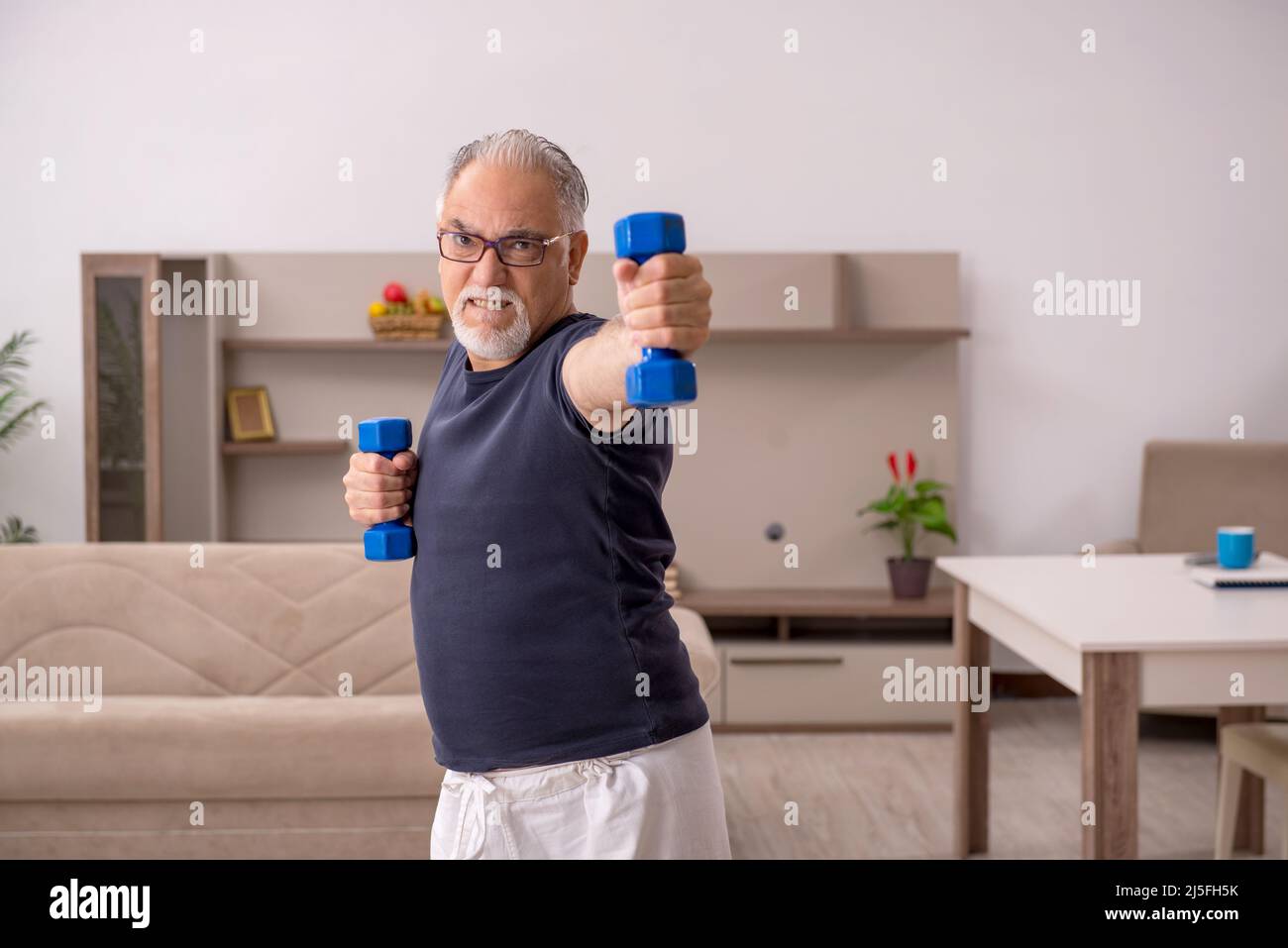 Old man doing sport exercises indoors Stock Photo - Alamy