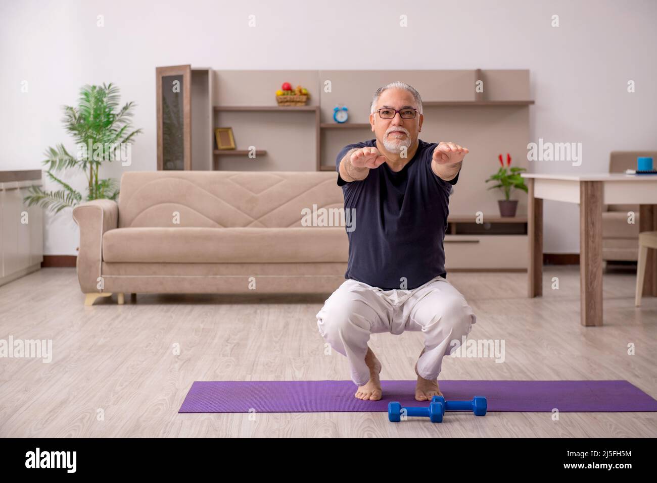 Old man doing sport exercises indoors Stock Photo - Alamy